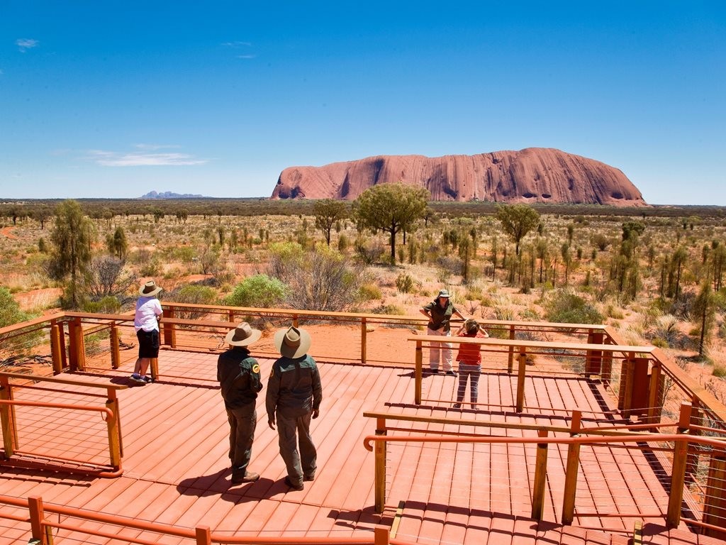 Visitors watch sunrise from Rocla concrete boardwalks in Uluru National ...